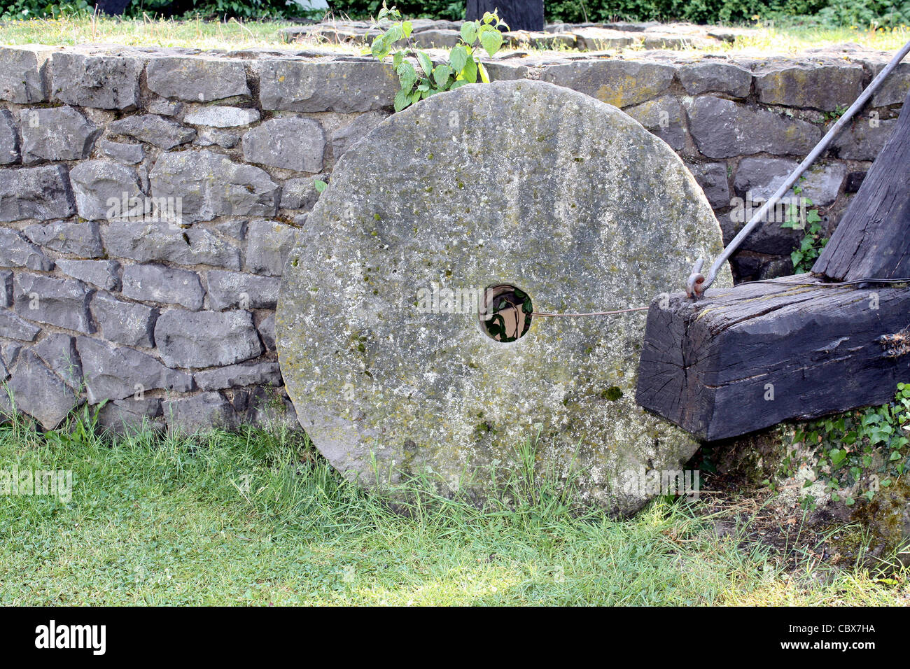 A old limestone mill stone at an old wall Stock Photo - Alamy