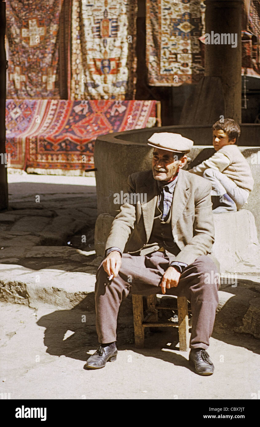 Old Kurdish man and child sit in the sun outside the carpet bazaar in ...