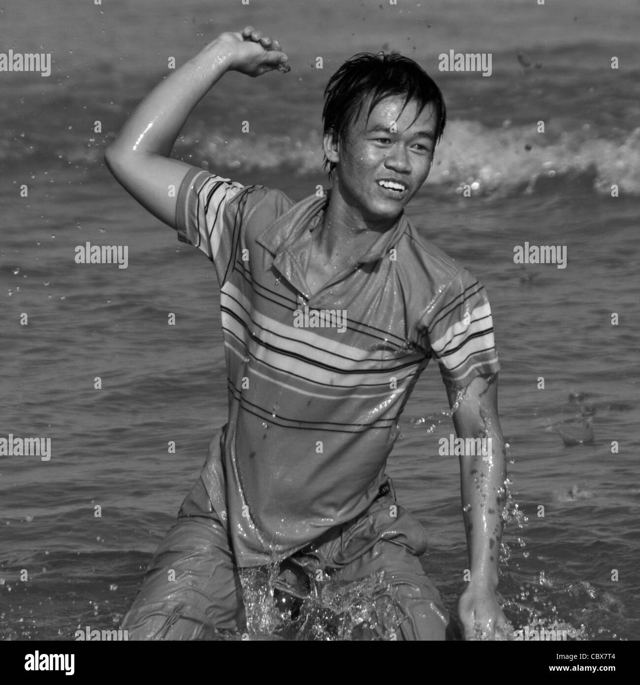 Vungtau, Vietnam. Young man throwing sand to his friends at the beach ...