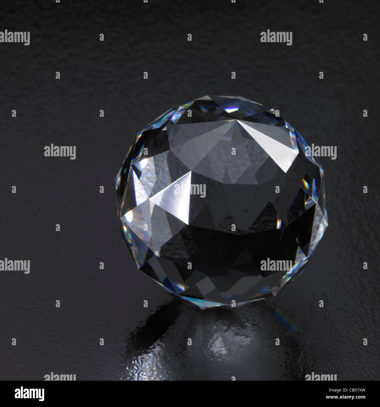 Studio photography of a round diamond made of glass in dark glossy back ...