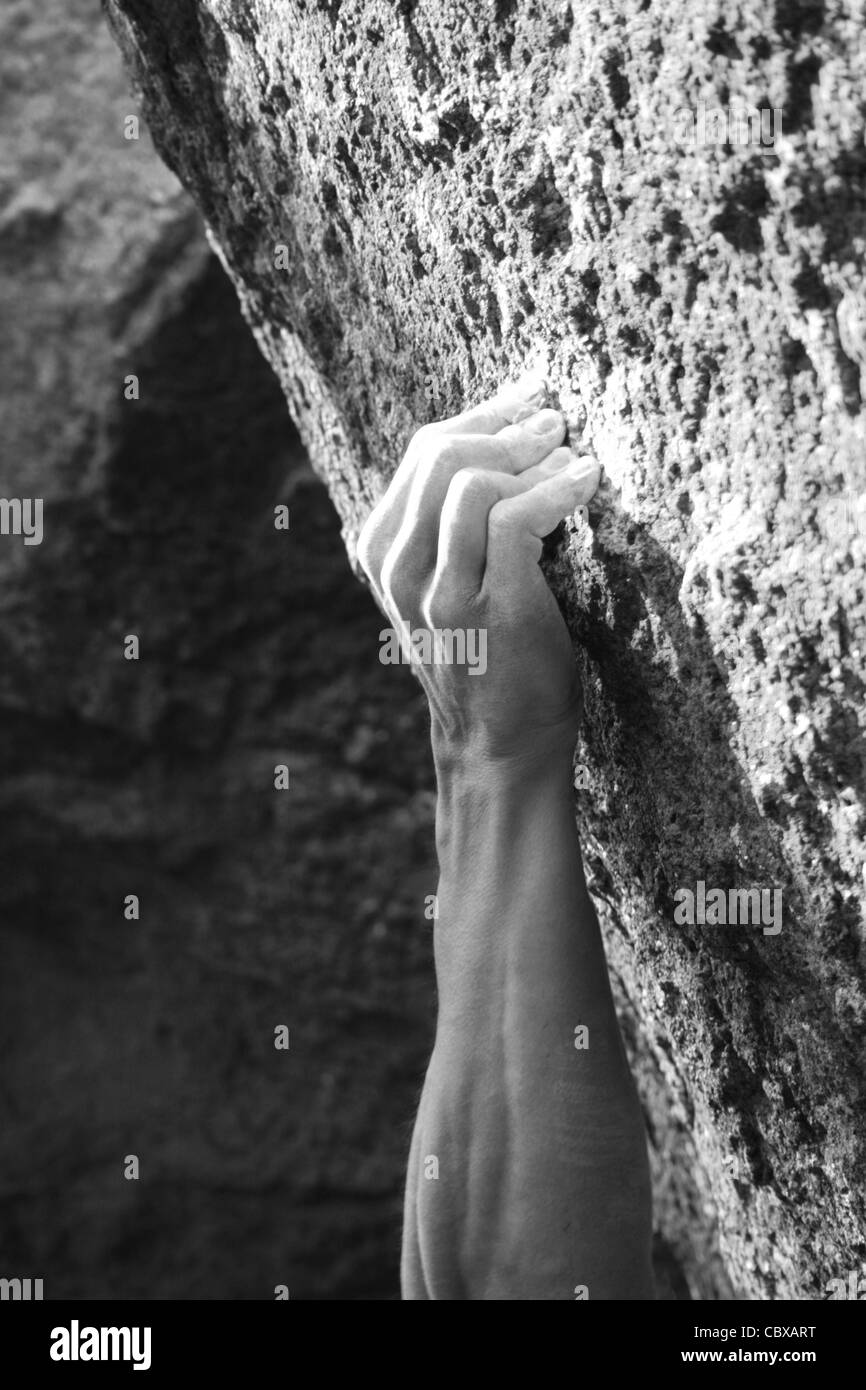 black and white image of a rock climber's hand crimping a small hold ...