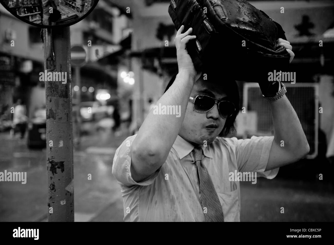 Kowloon, Hong Kong. Man using his bag as a cover from the rain Stock ...