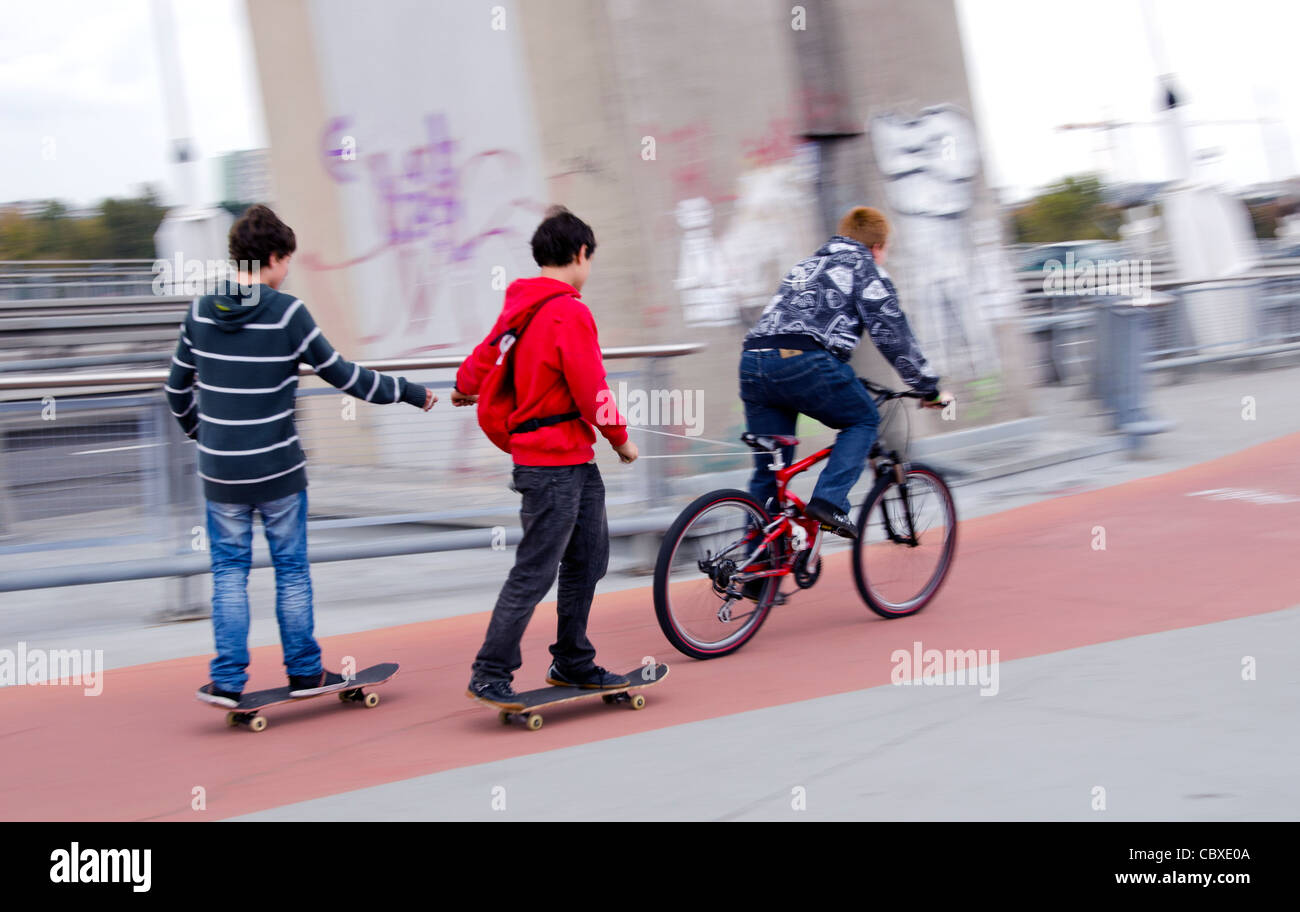 Teenagers riding bikes and skateboards on urban bicycle trail Stock ...