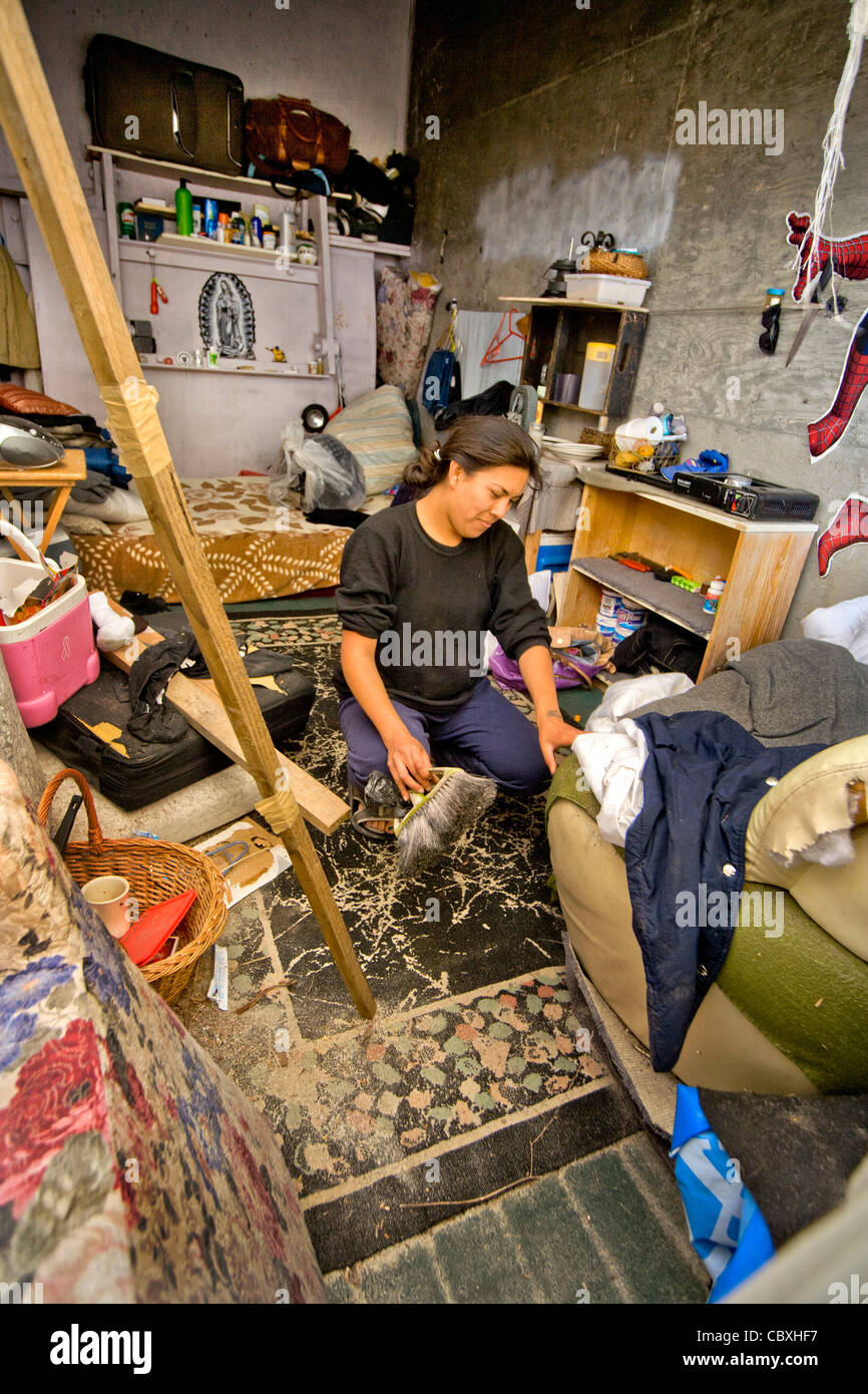 A homeless Hispanic military veteran cleans her jerry-built shelter ...