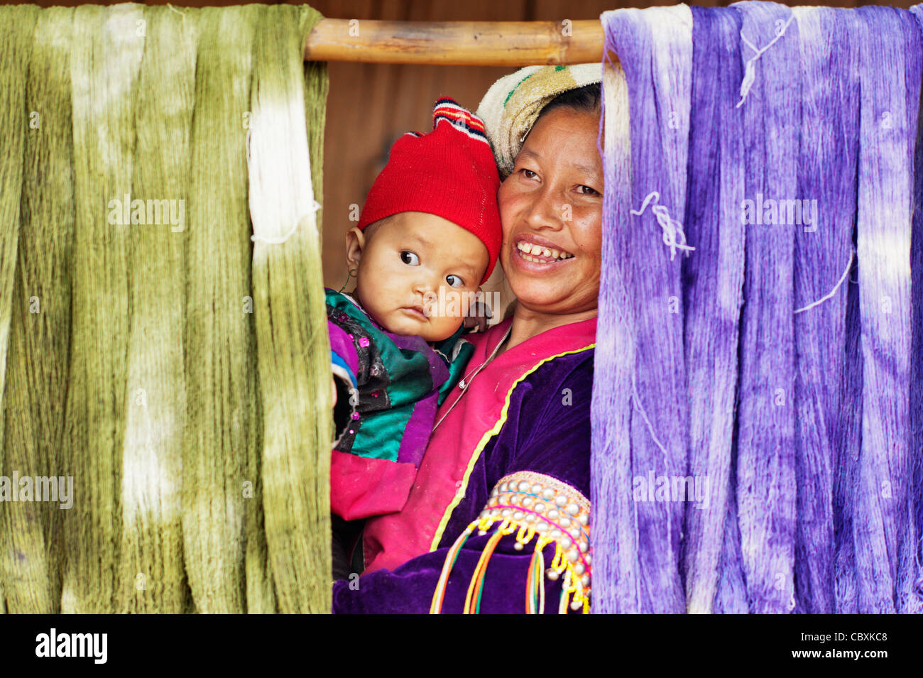 Palong mother and child looking out from between died thread hanging ...