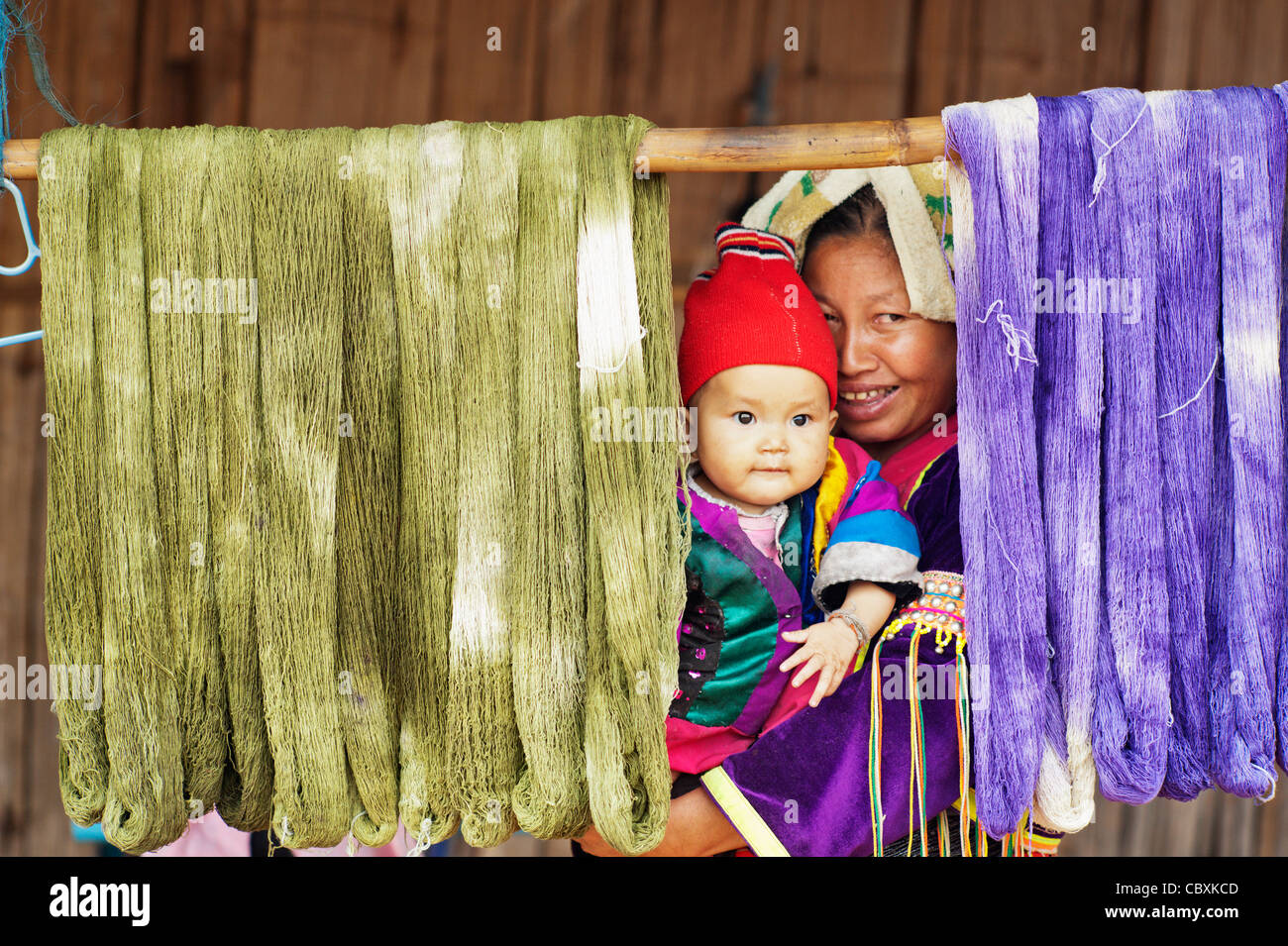 Palong mother and child looking out from between died thread hanging ...