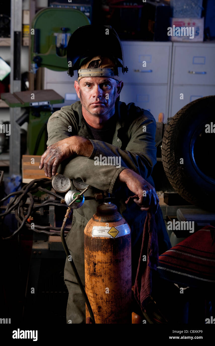 A grease covered blue collar working man takes a break, looking ...