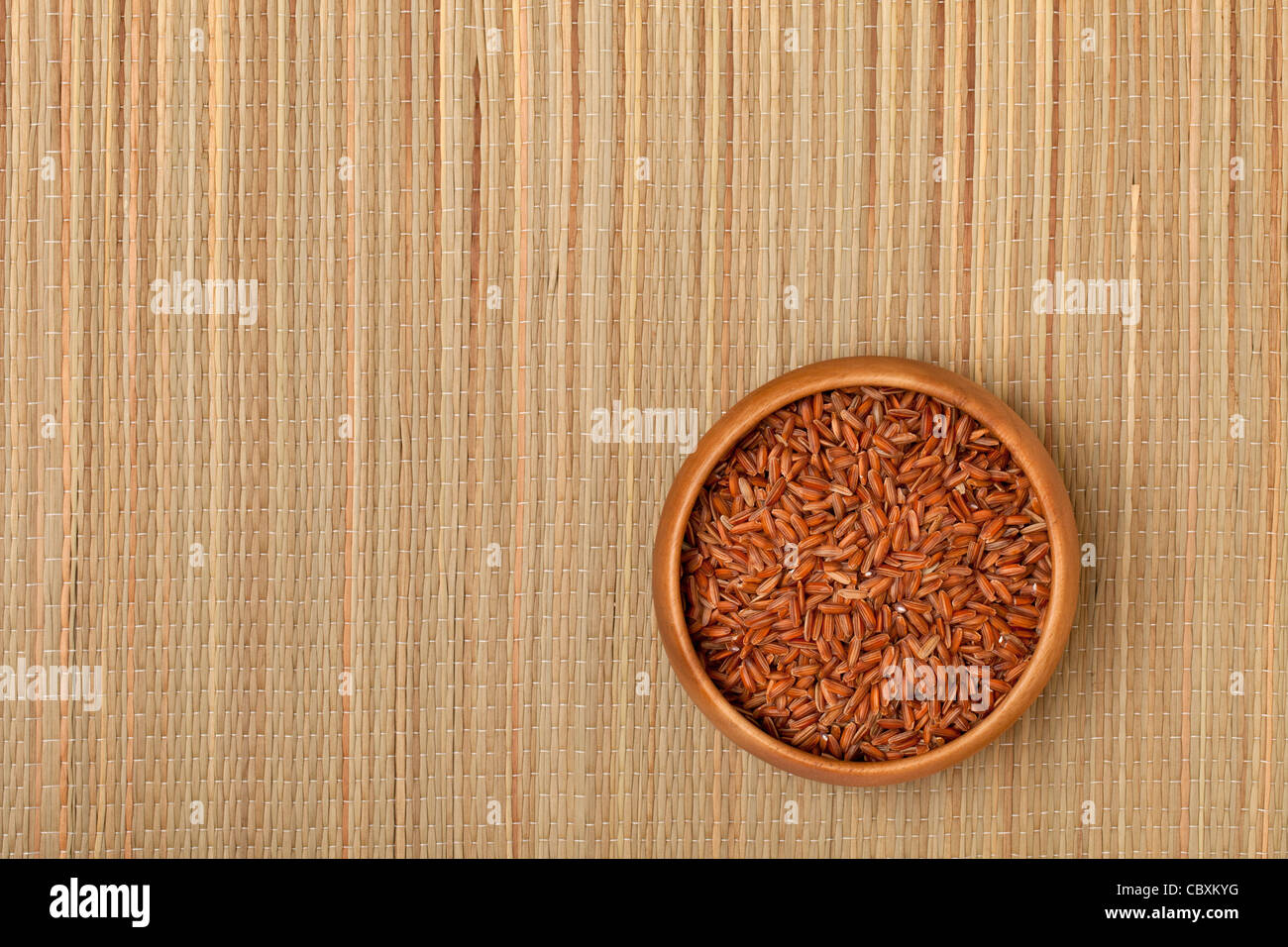 a small wooden bowl of brown rice on a grass mat Stock Photo - Alamy