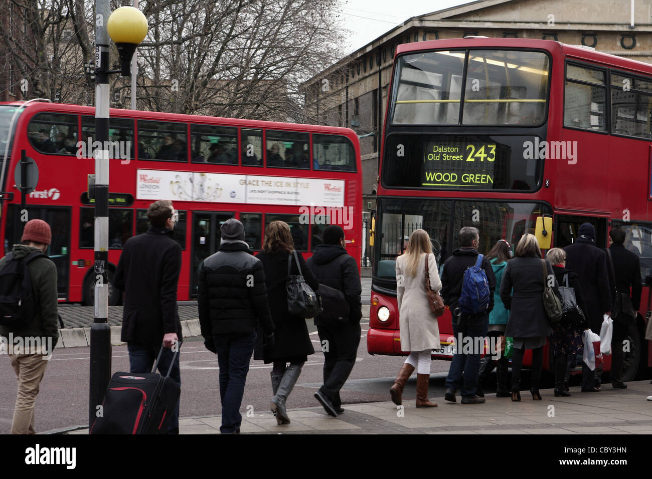 a queue of people waiting to board a red London bus Stock Photo - Alamy