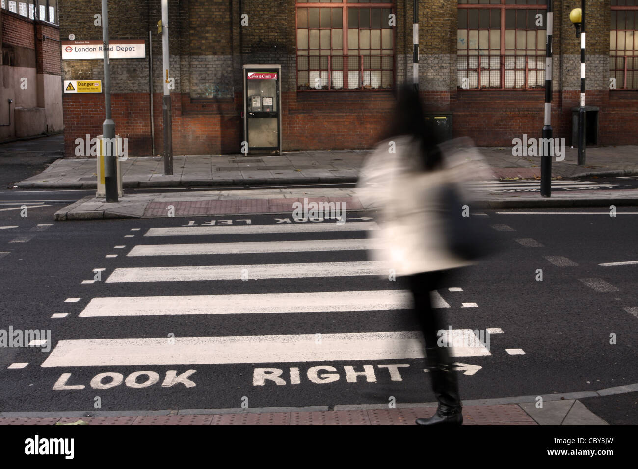 a female walks across a zebra crossing in London Stock Photo - Alamy