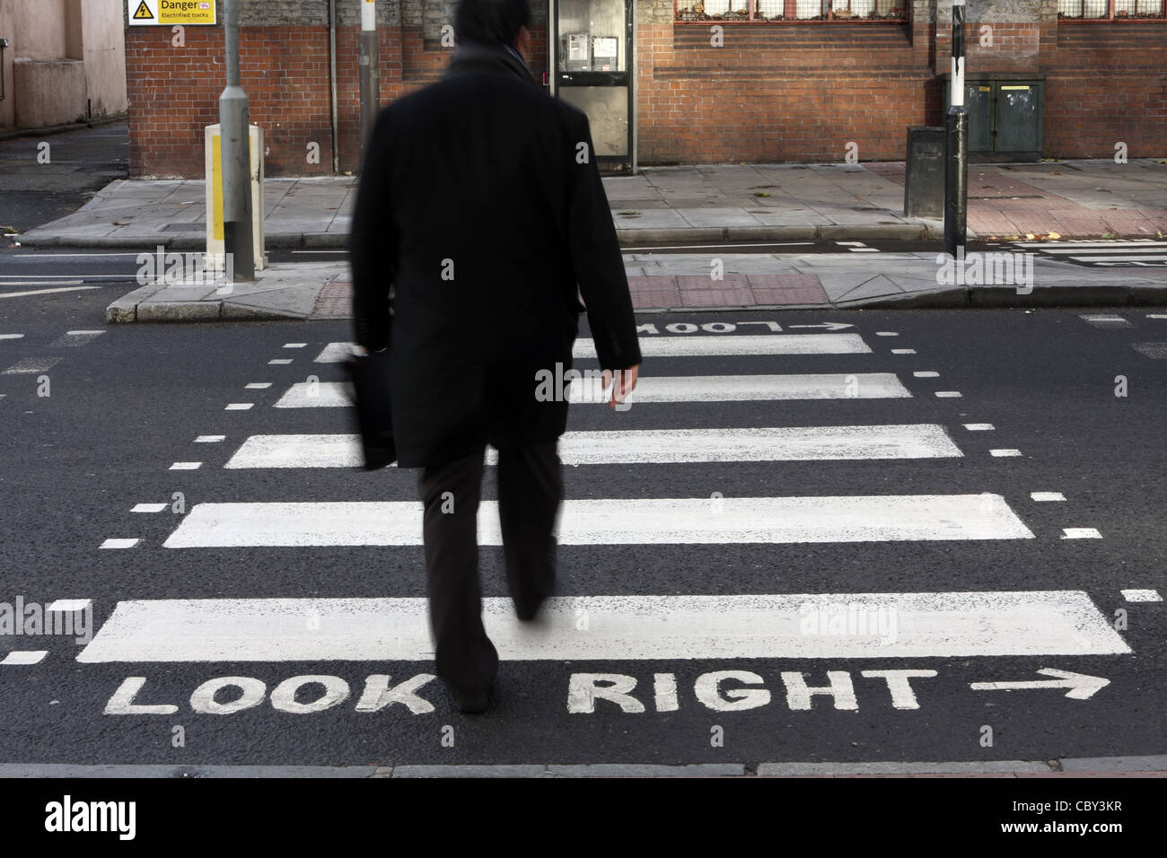 a male walks across a zebra crossing in London Stock Photo - Alamy