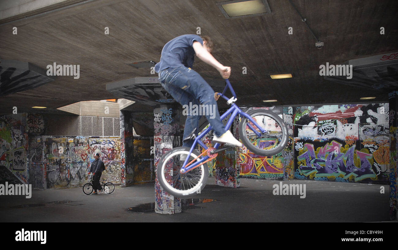 BMX rider pulling tricks in front of graffiti wall in London. The image ...