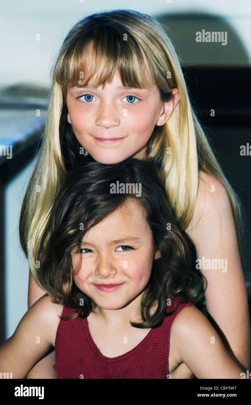 Portrait of two young girls sitting, one blond and one brunette in a ...