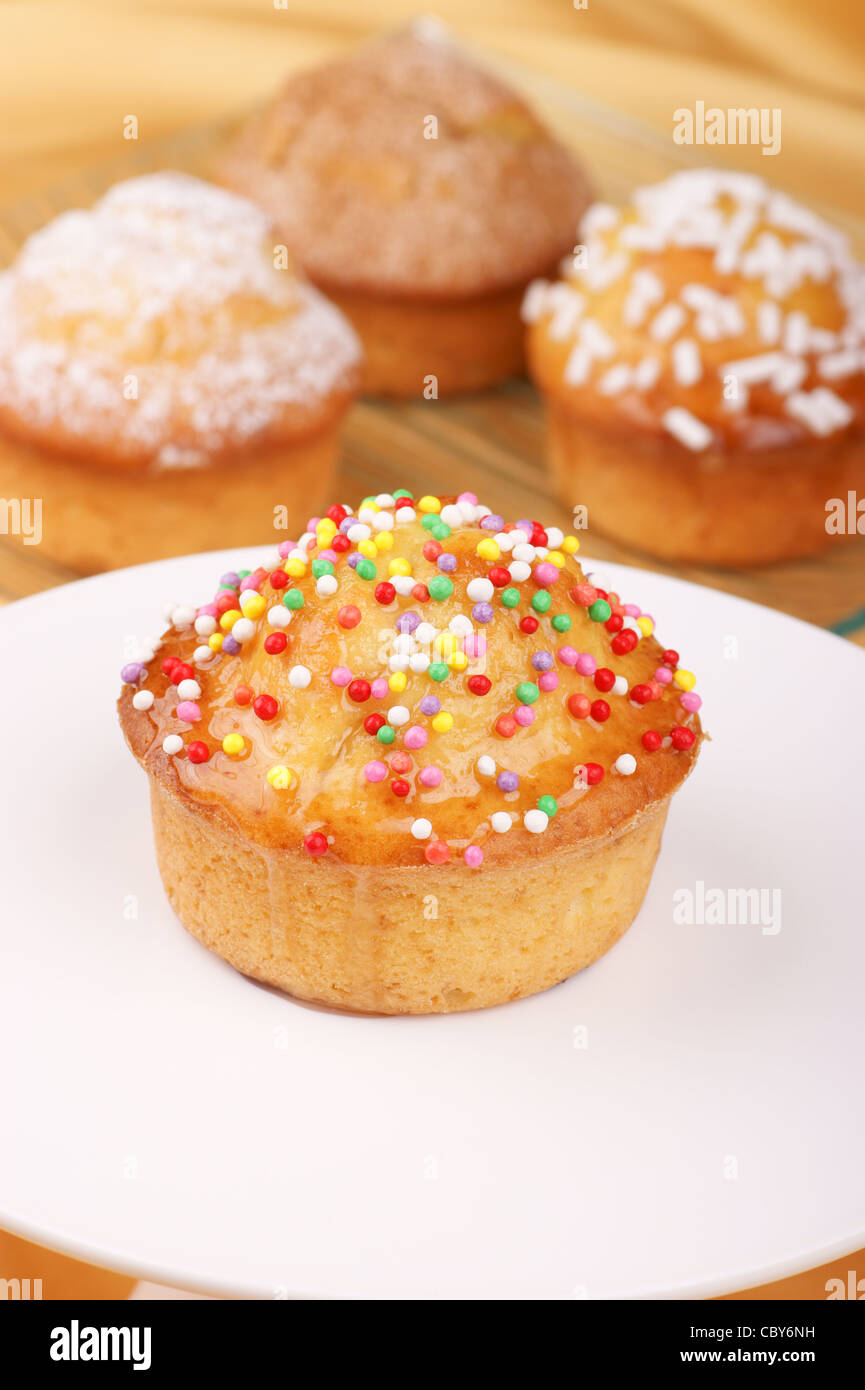 Muffin decorated with colored sugar grains on a cake stand and assorted ...