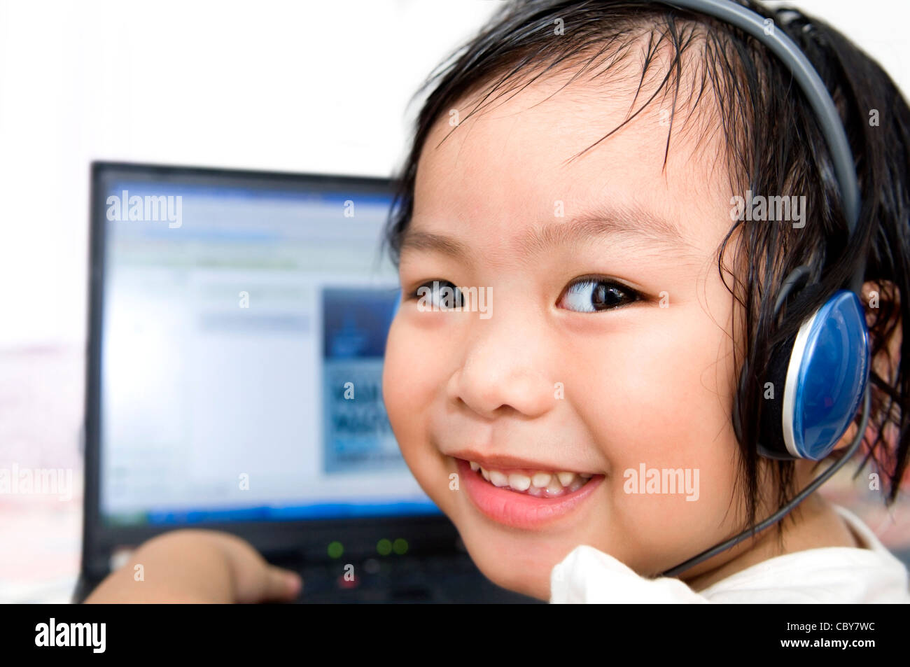 Young preschool girl, listening to music or a video on a laptop ...