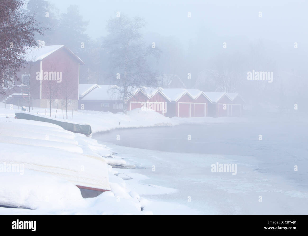 Snow covered upturned rowboats / skiffs / dinghies at riverbank and ...