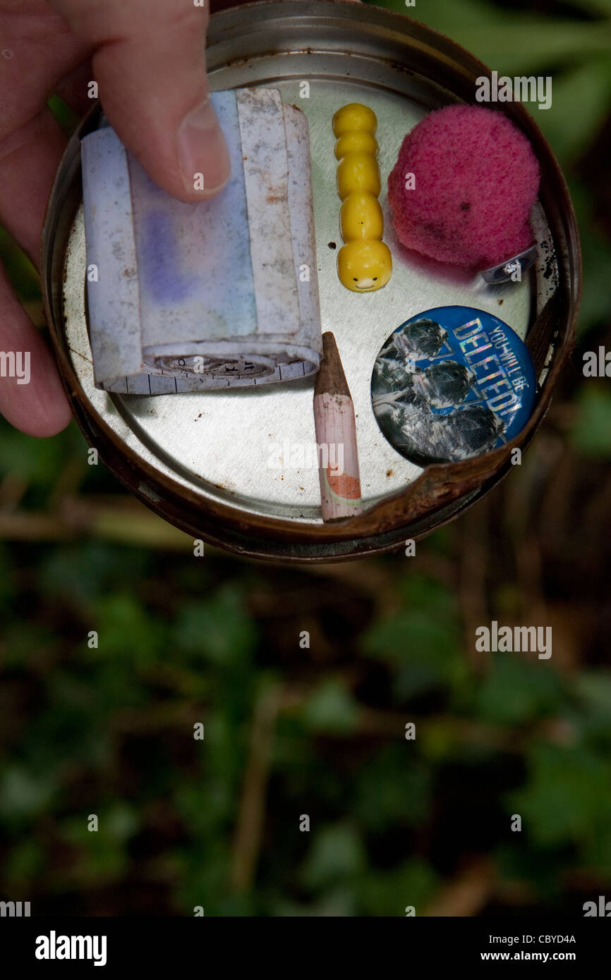 Person showing the contents of a small Geocache tin Stock Photo - Alamy