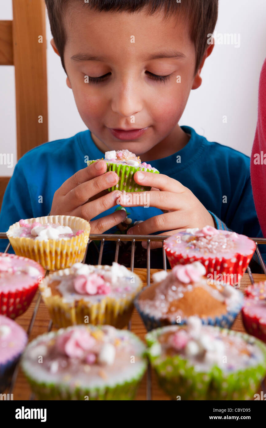 Young boy eating cupcakes alone Stock Photo - Alamy