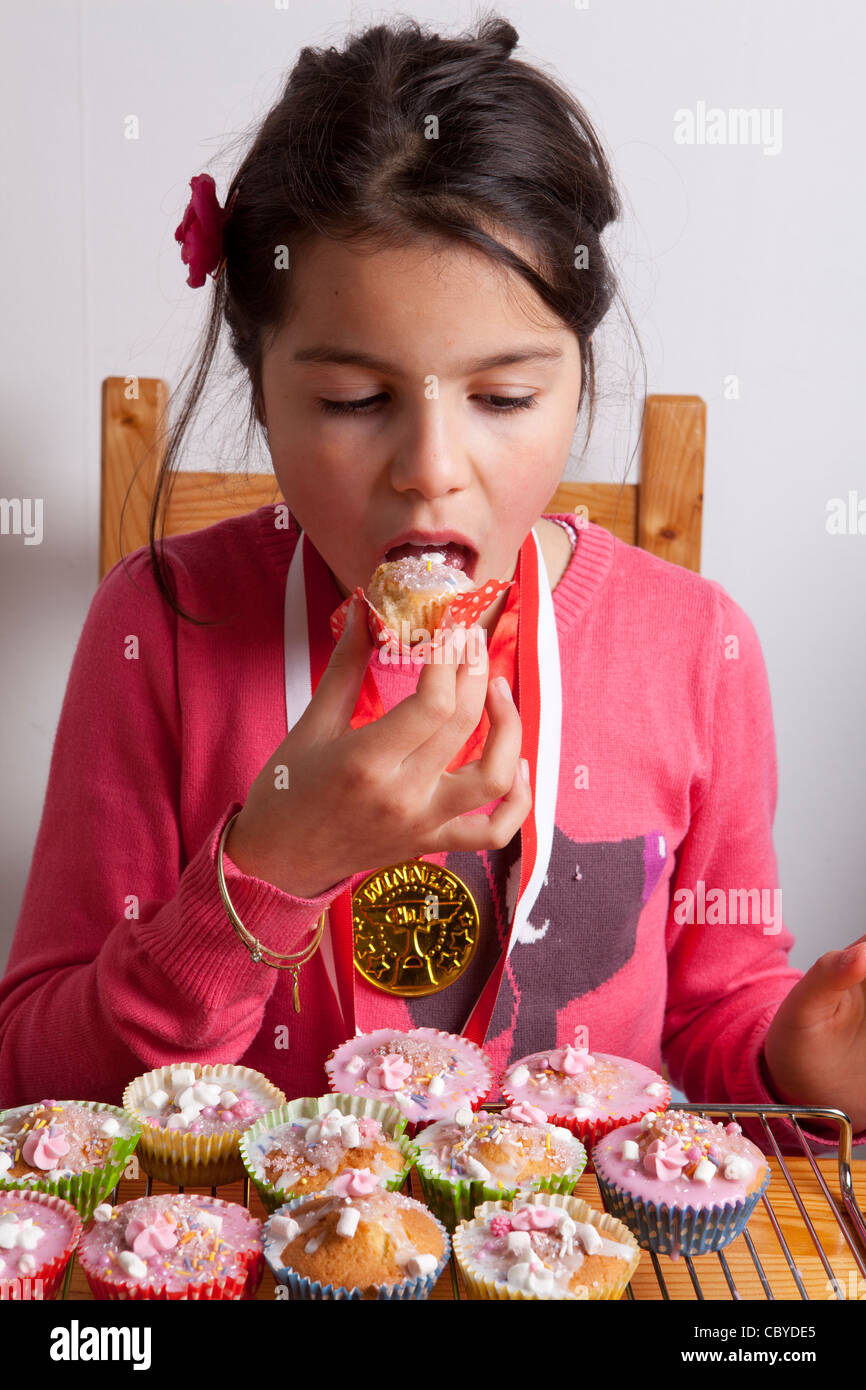 Young girl eating cupcakes alone Stock Photo - Alamy