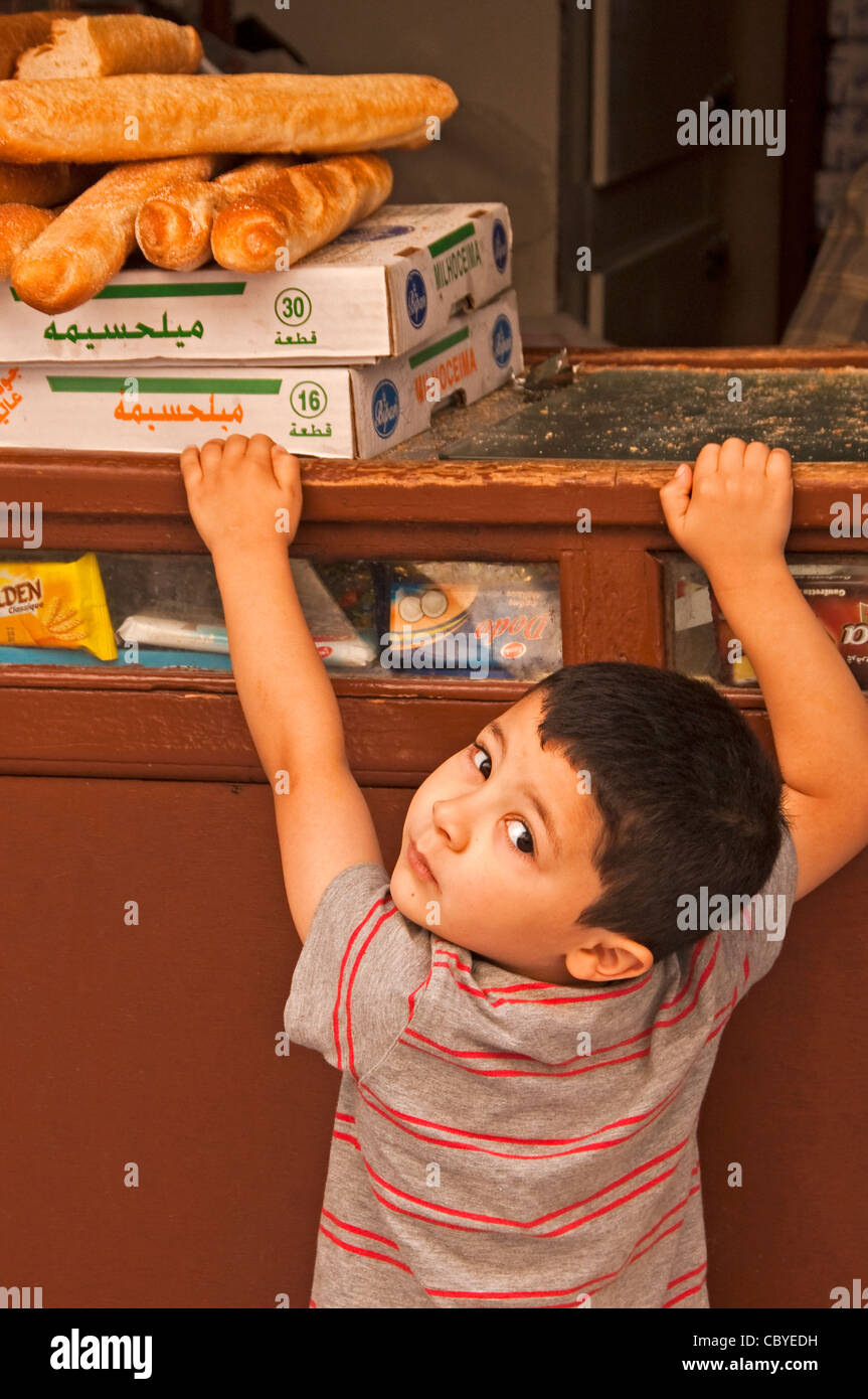 Boy reaching for bread in shop in Medina of Fez, Morocco Stock Photo ...