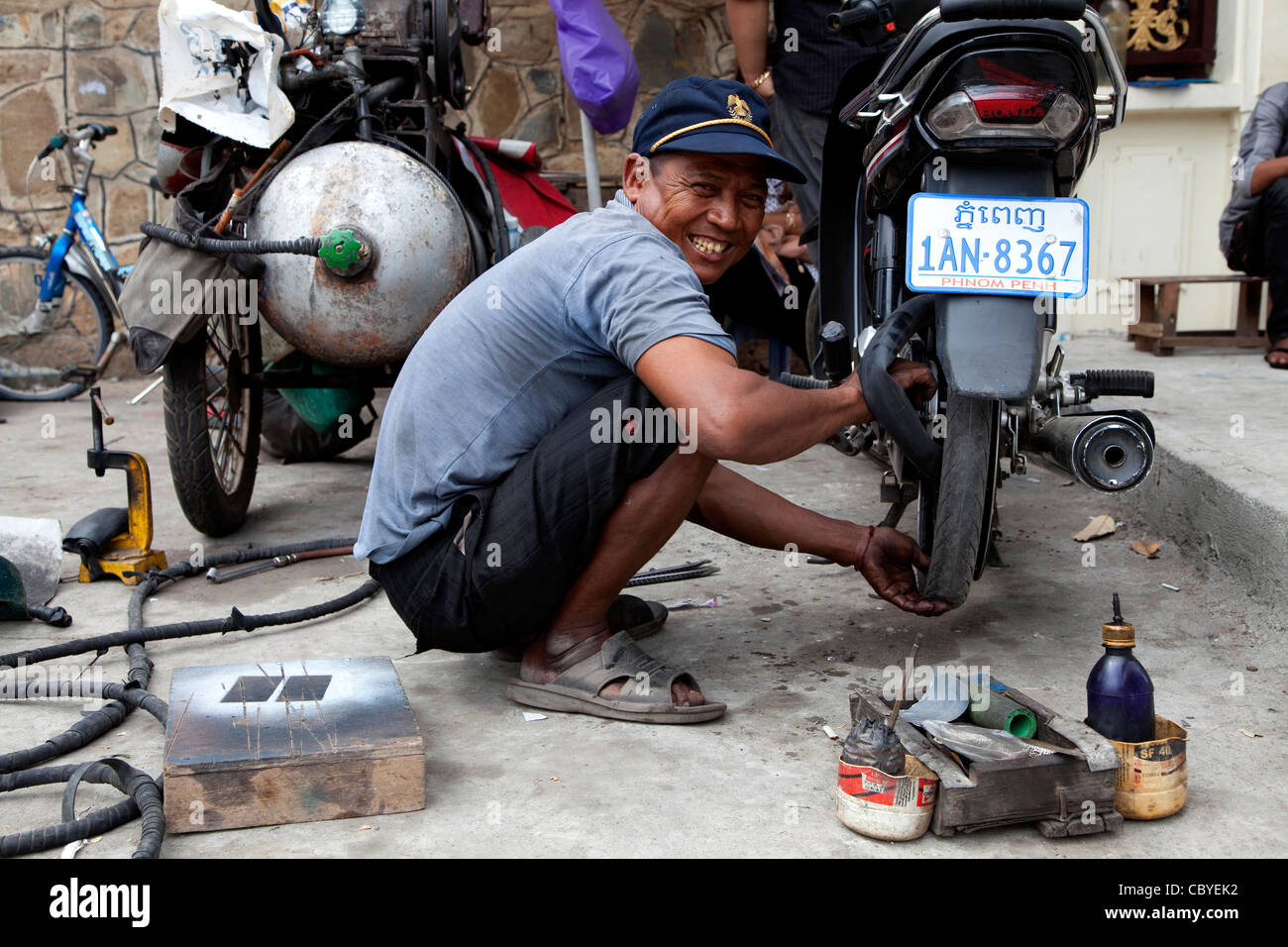Happy Asian man working in mechanic shop at repairing flat tire, Phnom ...
