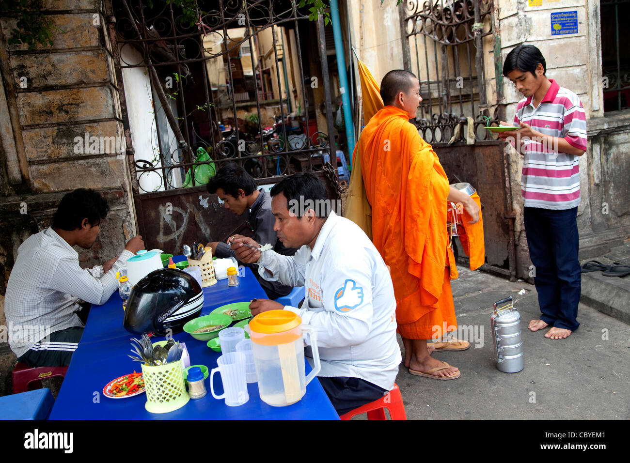 Buddhist monk receiving food and rice offer at street restaurant, Phnom ...