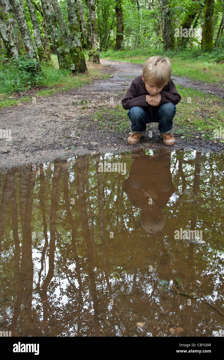 CHILD LOOKING AT HIS REFLECTION IN A PUDDLE OF WATER, A WALK IN THE ...