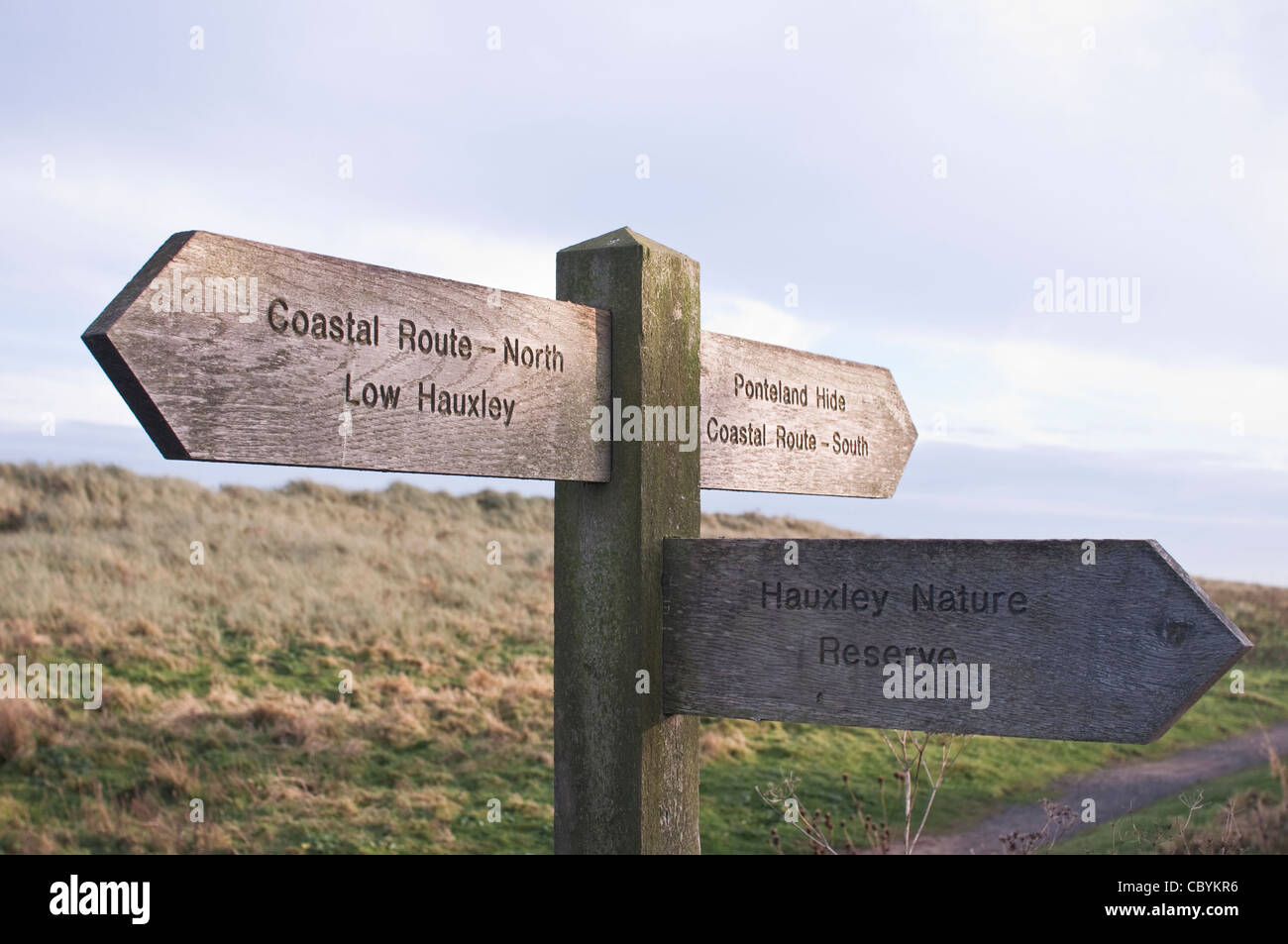 A wooden signpost pointing to Hauxley Nature Reserve, by a public ...