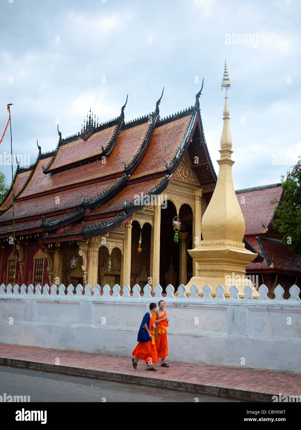 Two orange-clad apprentice Buddhist monks walk by Wat Sen Temple in ...