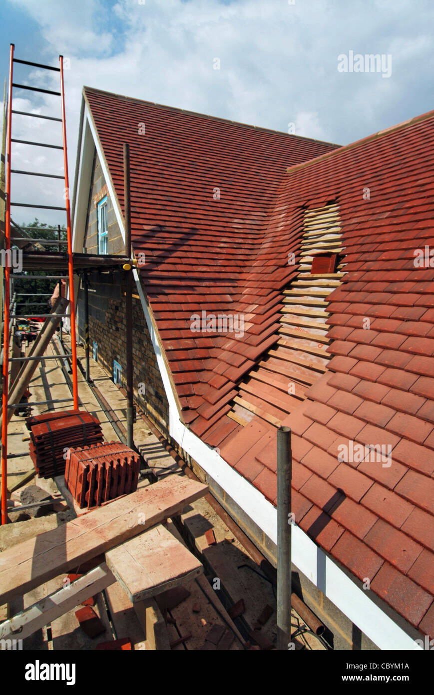 Scaffolding around detached house & roof tiling work in progress during ...
