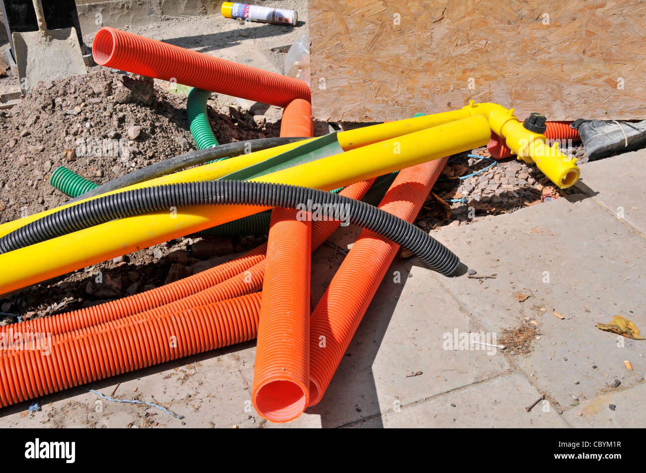 Pavement disruption jumbled heap of colourful plastic tube & pipe used ...
