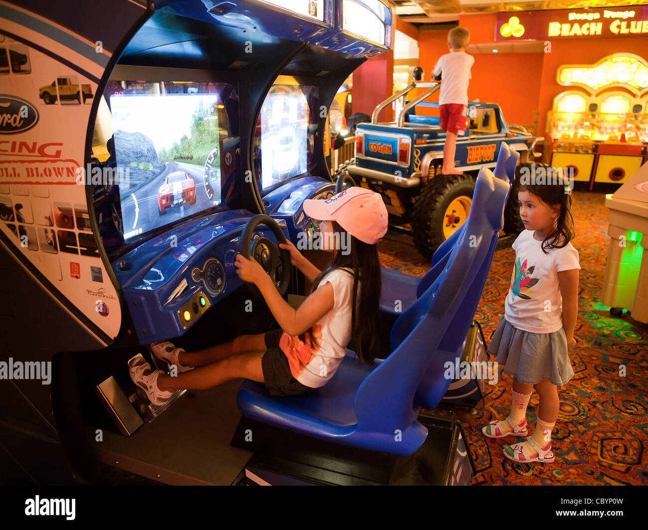 One young girl plays on an arcade machine whilst another watches on ...