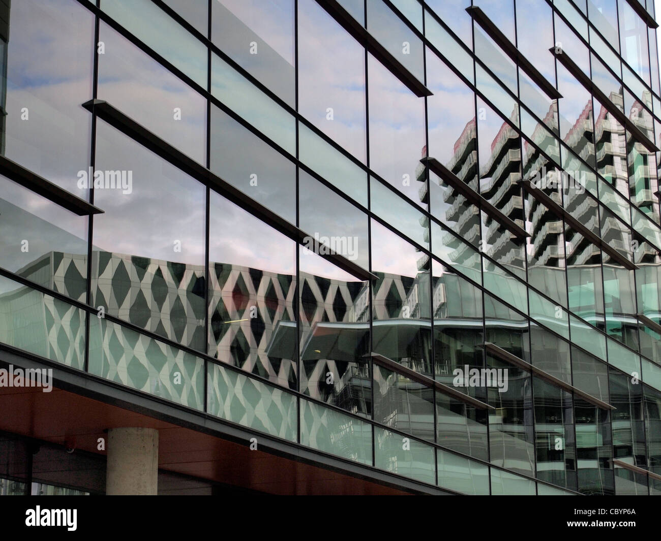 Glass facade at Salford Quays reflecting distorted geometric buildings ...