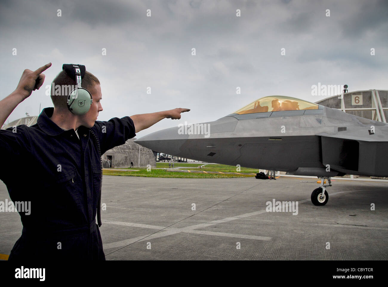 A crew chief signals the pilot of an F-22 Raptor to prepare to taxi ...