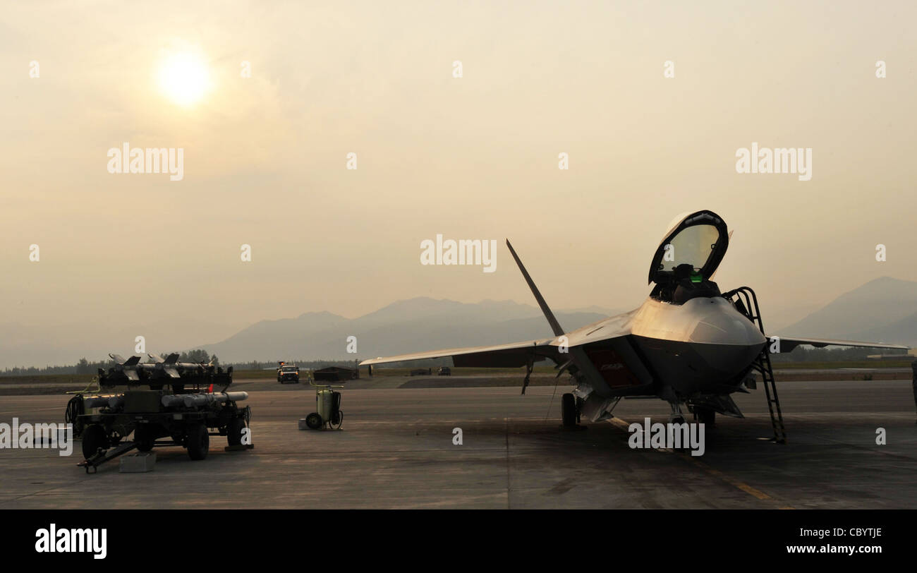 Through a smoky haze, the sun beams down on an F-22 Raptor July 10 on ...