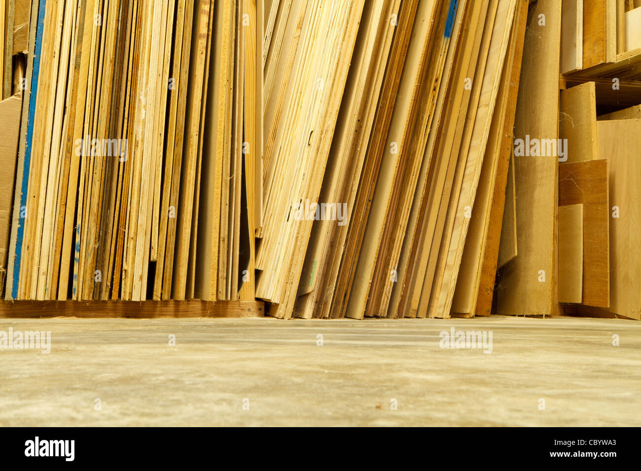 Sheets of various types of plywood are stacked on end in a woodworkers ...