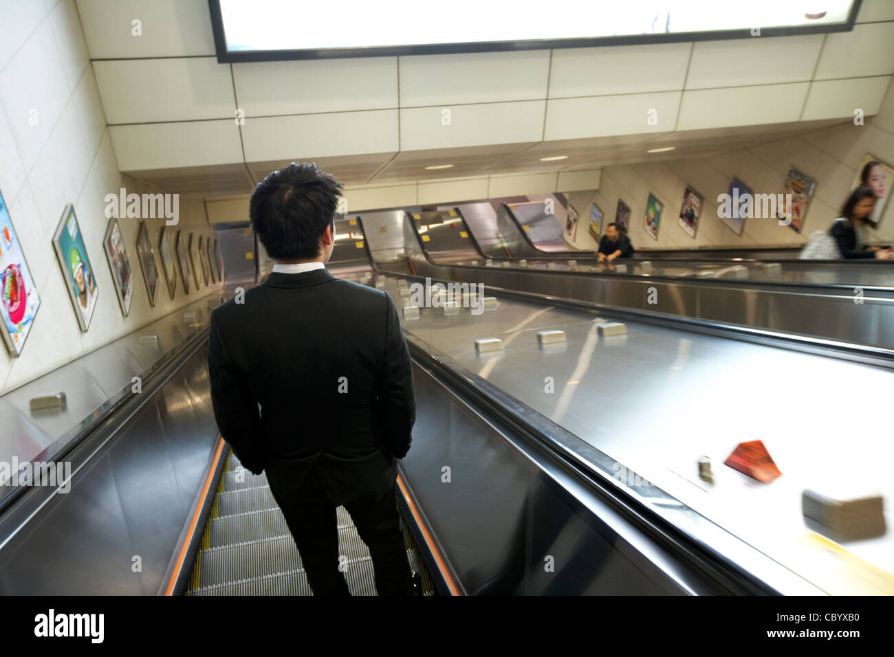 young chinese businessman using down escalator in hong kong mtr public ...