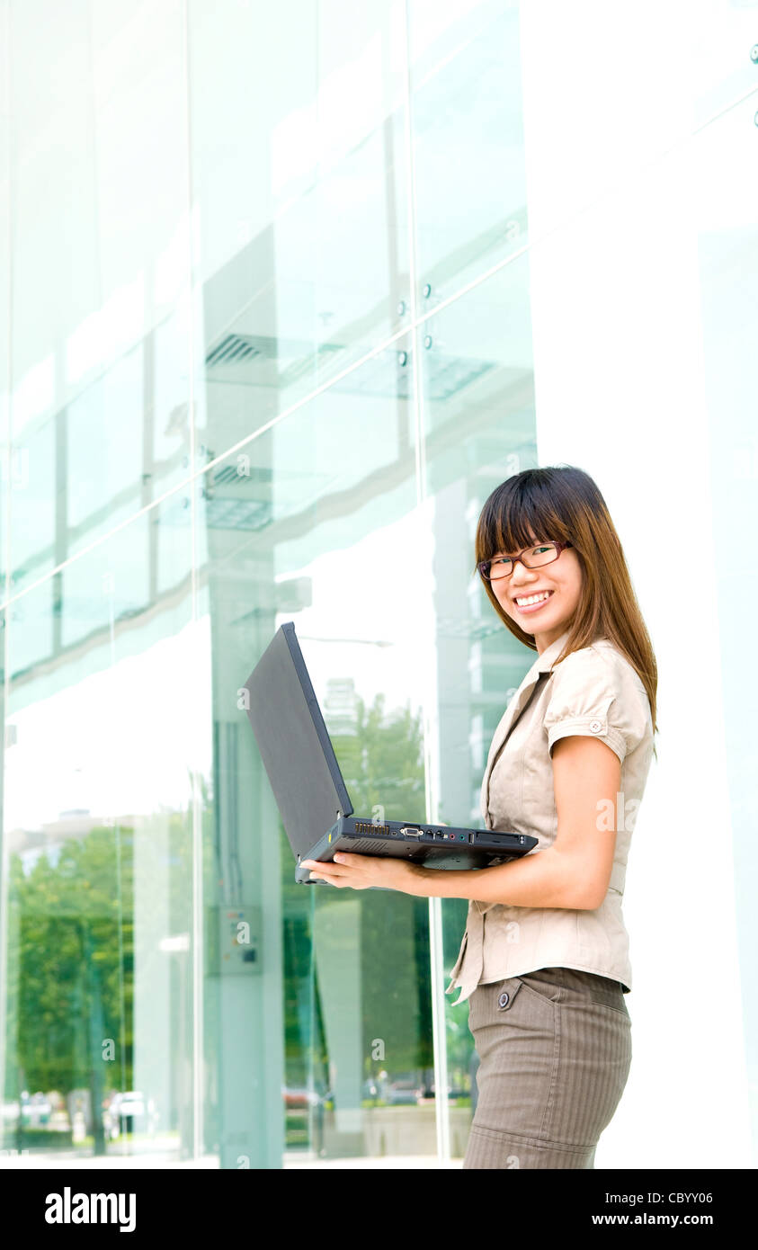 Asian female with laptop outside a modern building Stock Photo - Alamy