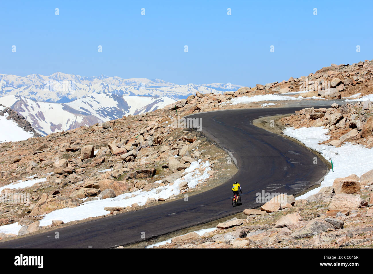 A cyclist climbs a high mountain road in the Colorado Rocky Mountains ...