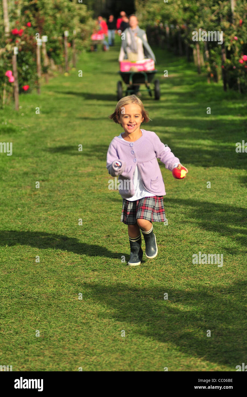 LITTLE GIRL RUNNING WITH AN APPLE IN AN ORCHARD Stock Photo - Alamy