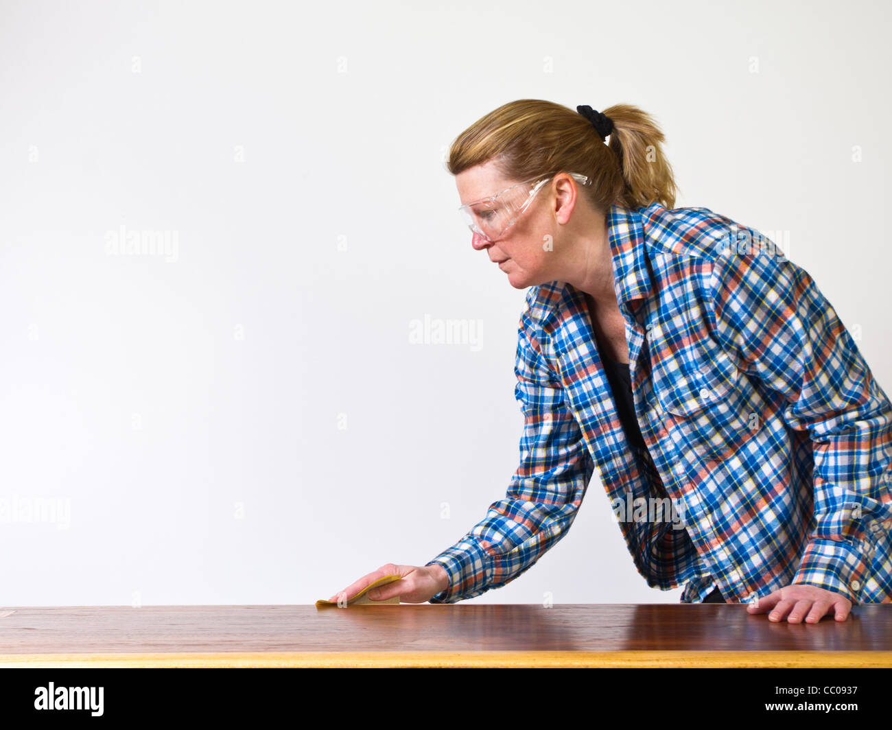 Woman sanding and varnishing a table Stock Photo - Alamy