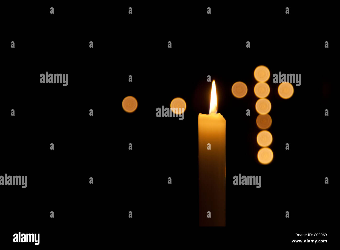 A burning candle with several more burning candles forming a cross in ...