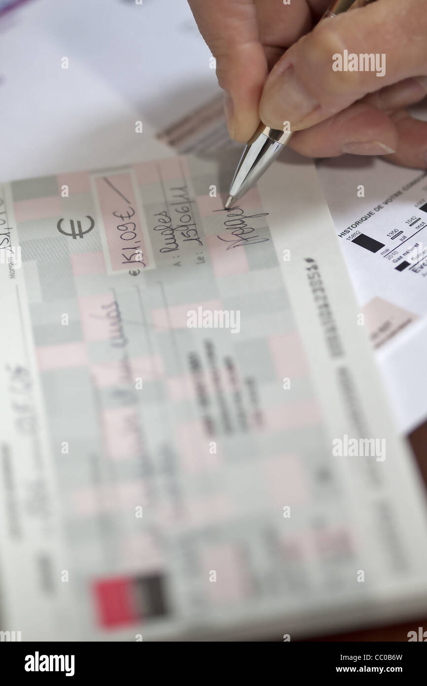 WOMAN SIGNING A CHECK TO PAY A BILL Stock Photo - Alamy