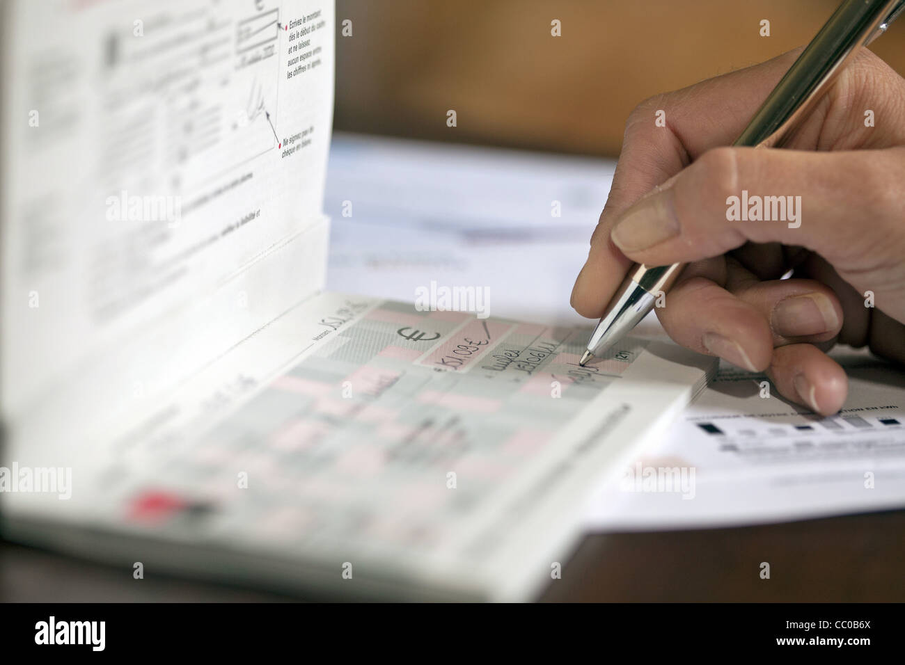 WOMAN SIGNING A CHECK TO PAY A BILL Stock Photo - Alamy