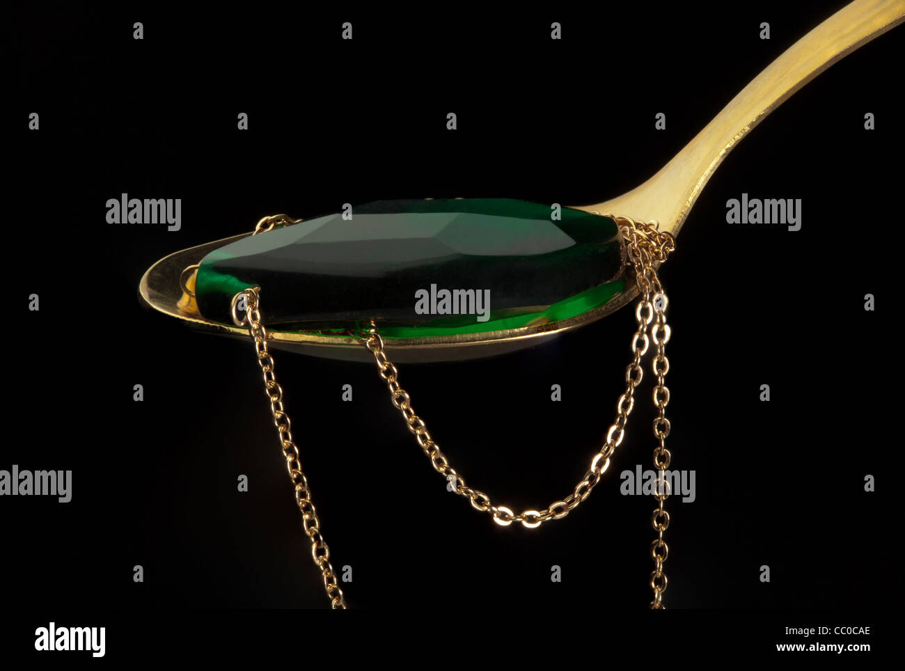 Golden spoon with coulomb from green stone and chain Stock Photo - Alamy