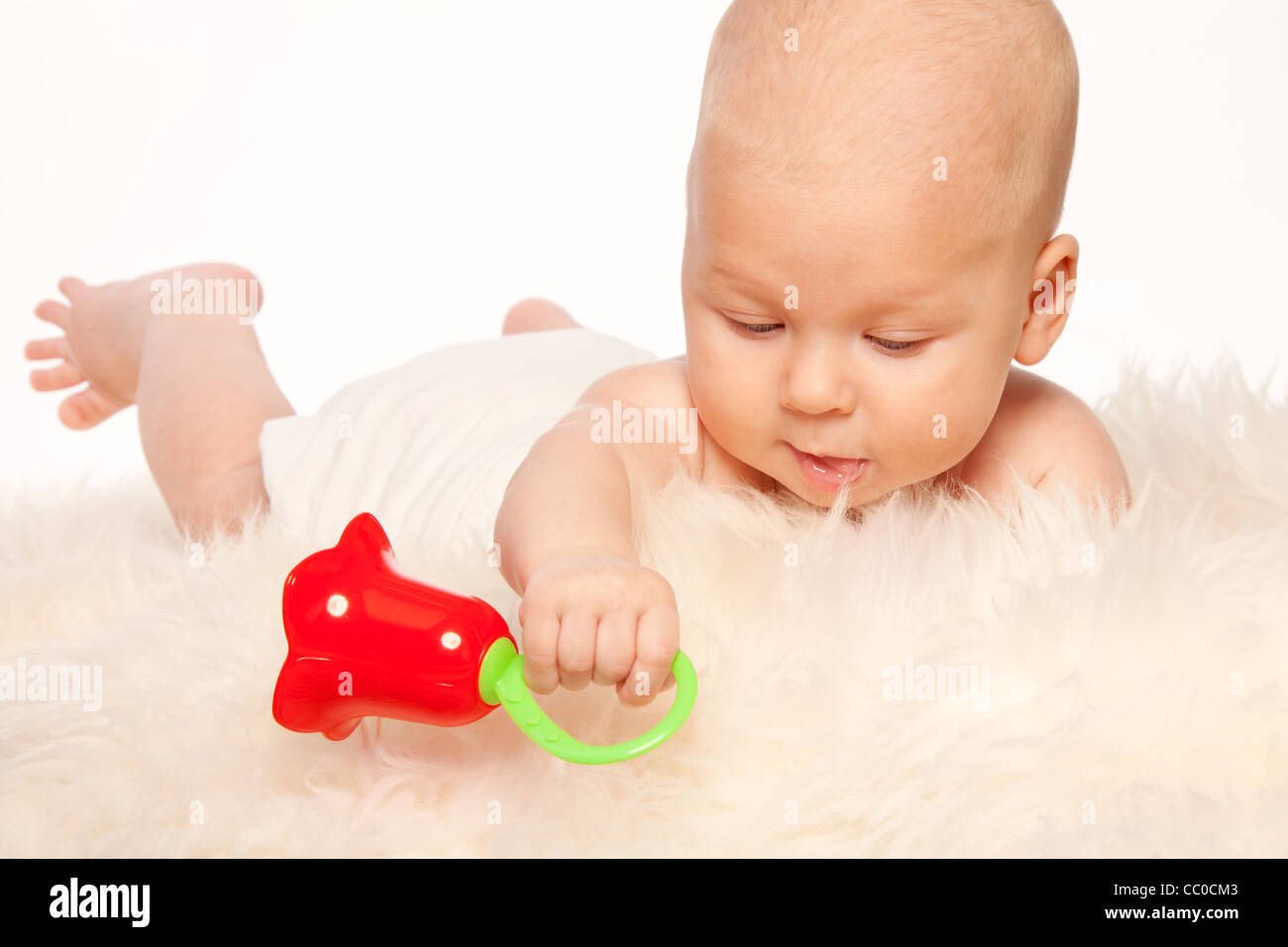 Baby playing with rattle laying in the soft fur bed Stock Photo - Alamy