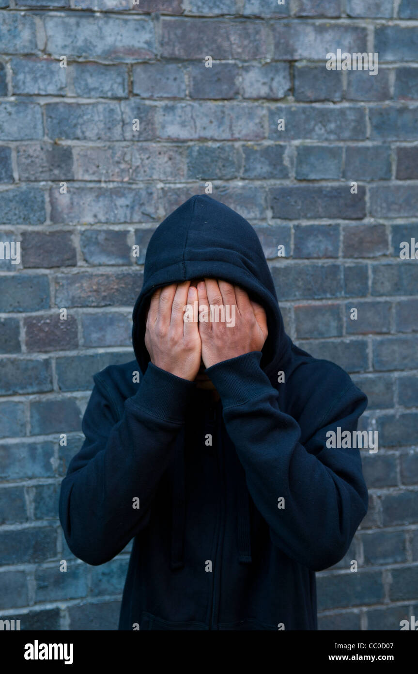 Hooded male head in hands Stock Photo - Alamy