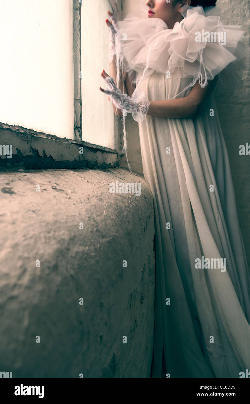 Sad young woman wearing vintage dress waiting by the window Stock Photo ...