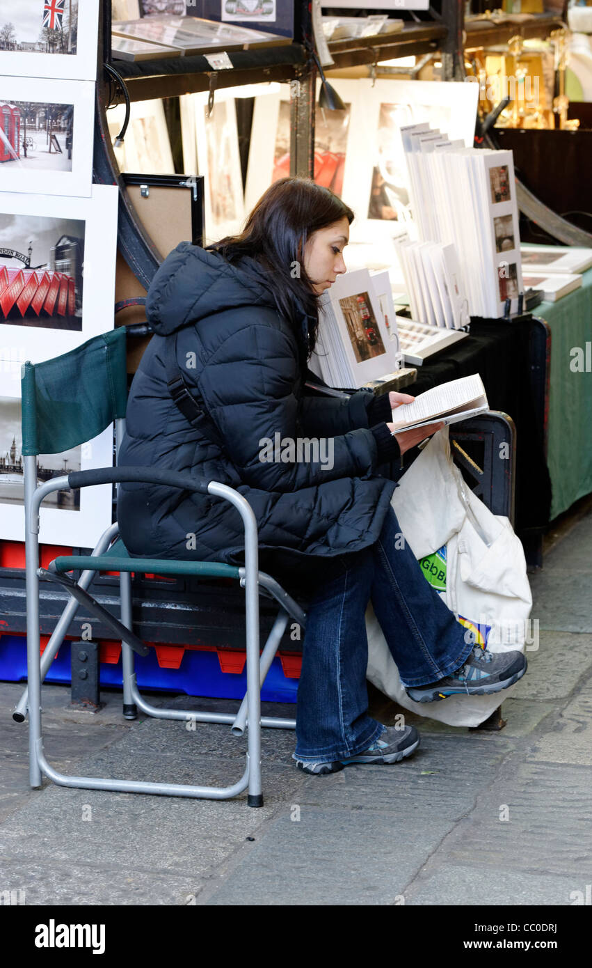 Covent Garden trader reading a book on her stall Stock Photo - Alamy