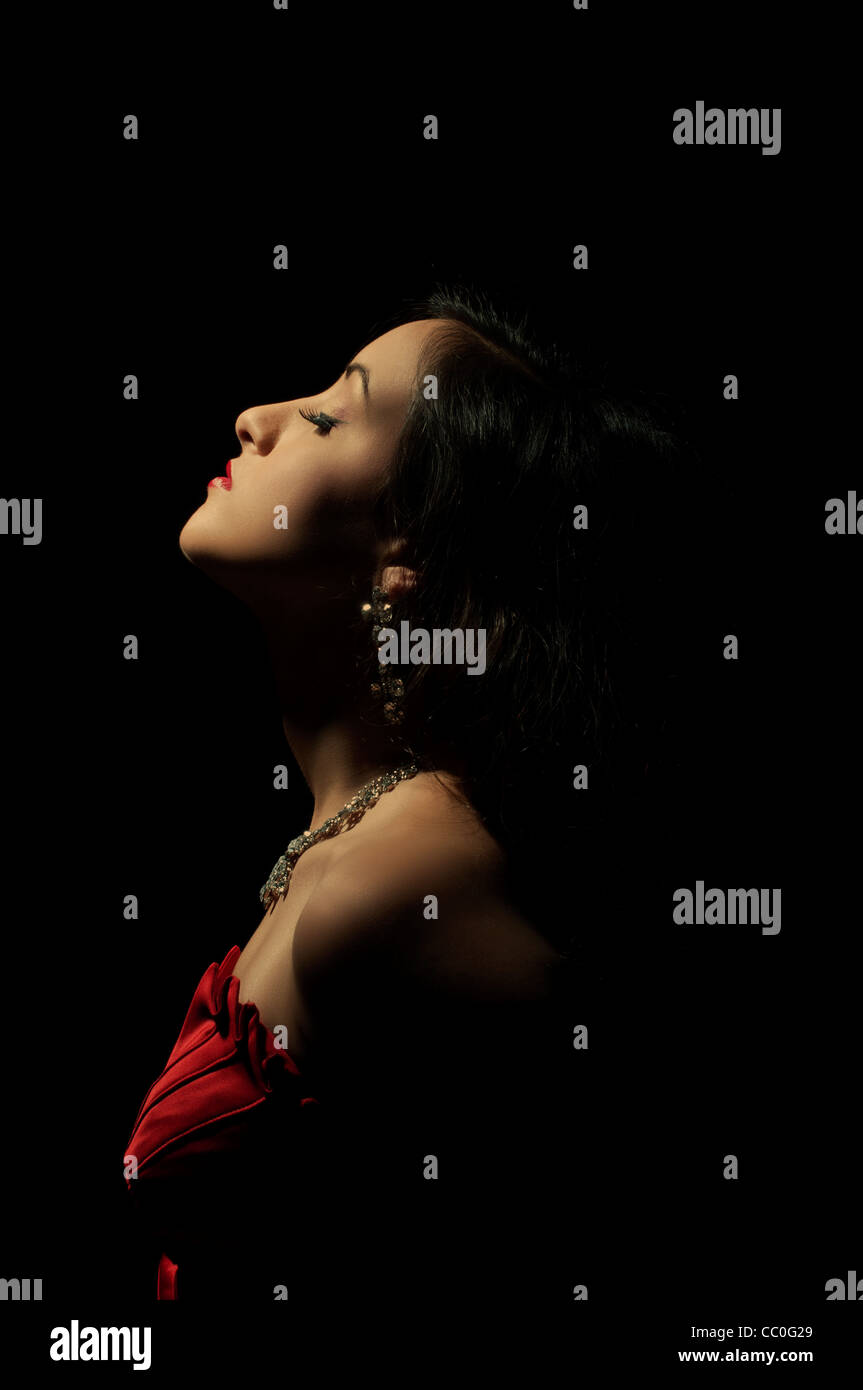 Beautiful woman in red dress standing in the dark Stock Photo - Alamy